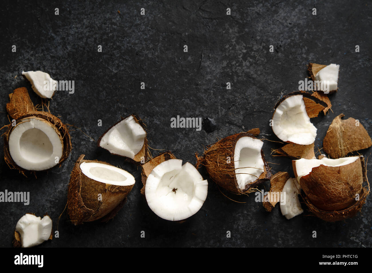 Cracked coconut arranged on dark textured background. Horizontal image ...