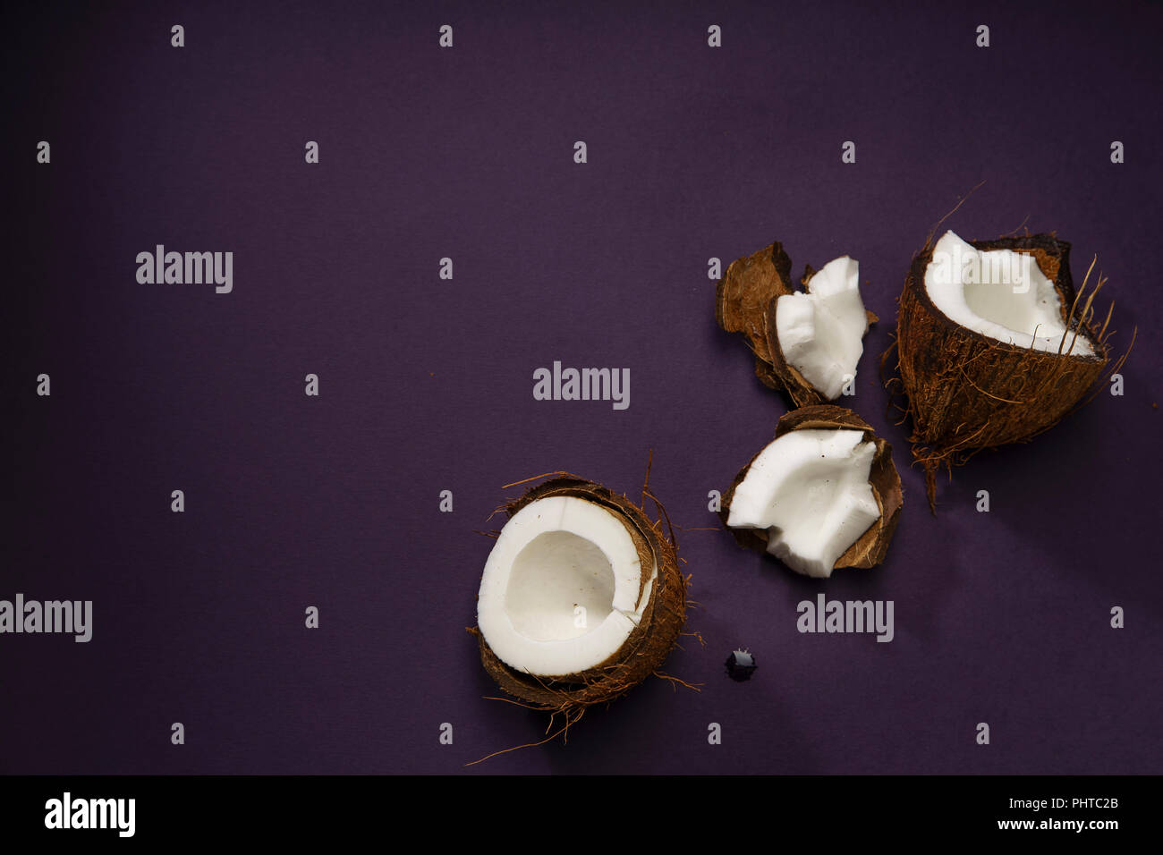 Cracked coconut arranged on dark purple background with copy space ...