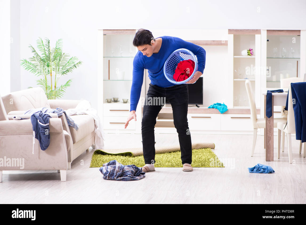 Young man collecting dirty clothing for laundry Stock Photo - Alamy