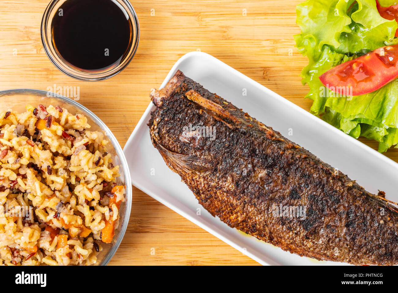 cooked fish with rice and vegetables on wooden background Stock Photo ...