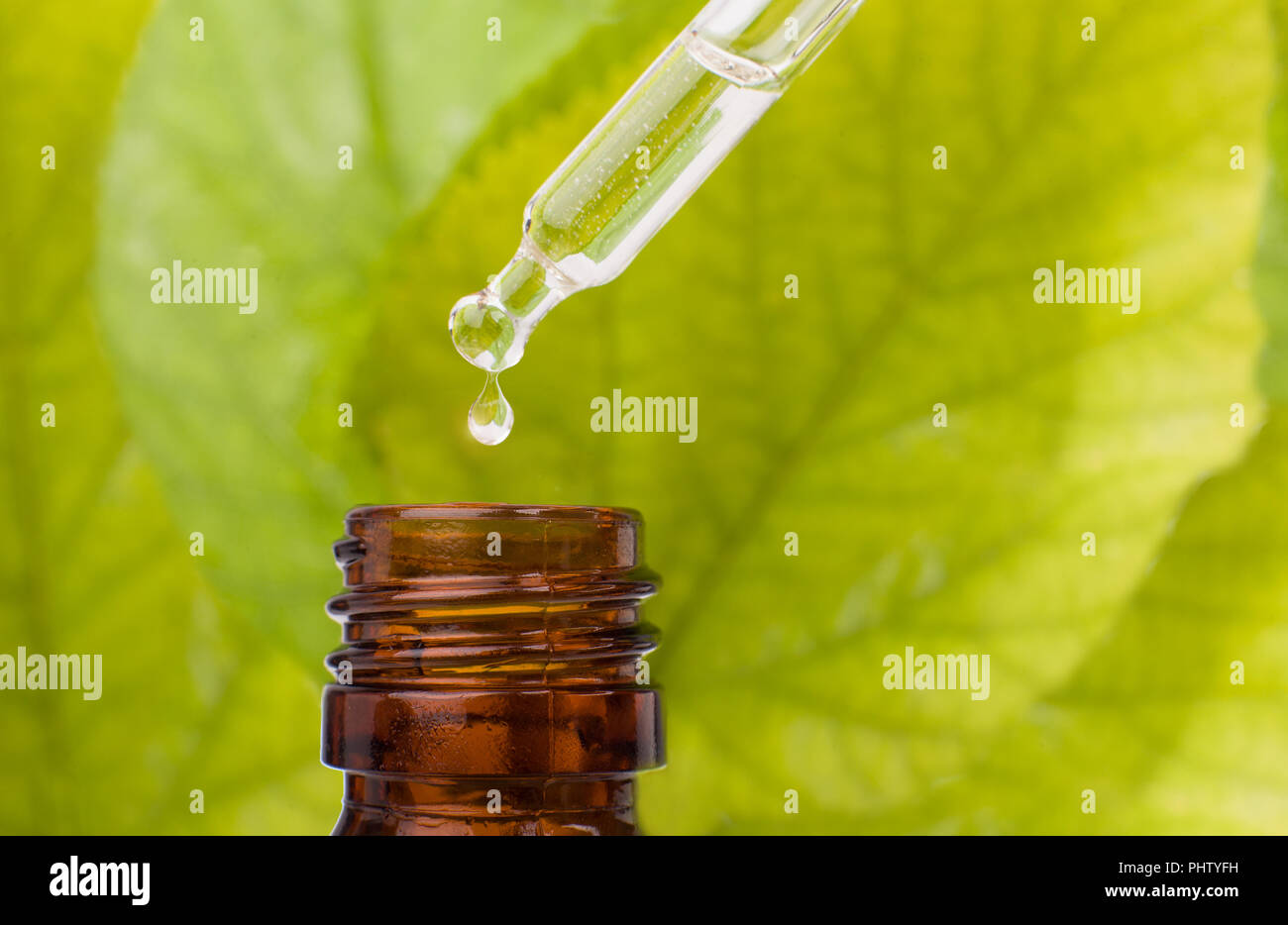 Dropper over essential oil bottle. Dropper with brown bottle and green ...