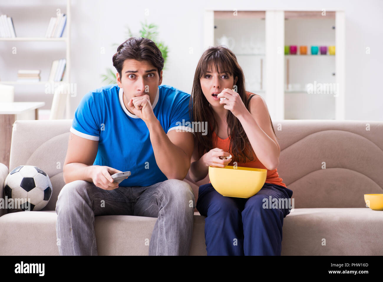 Young man watching football with his wife at home Stock Photo - Alamy
