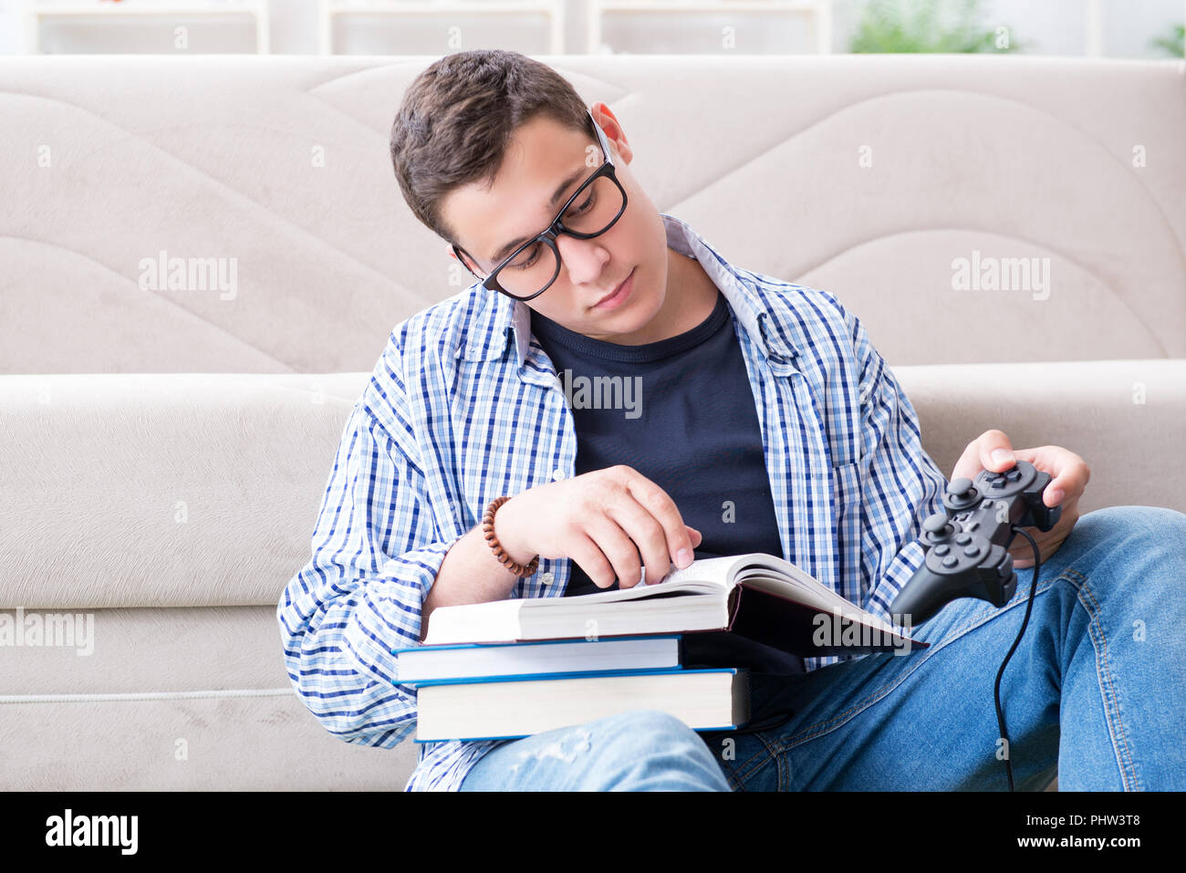 Young student trying to balance studying and playing games Stock Photo ...