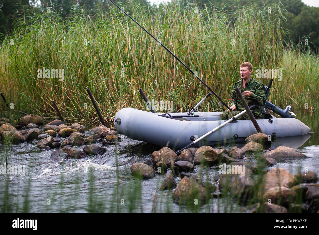 Fisherman on rubber boat catching fish on the lake Stock Photo - Alamy