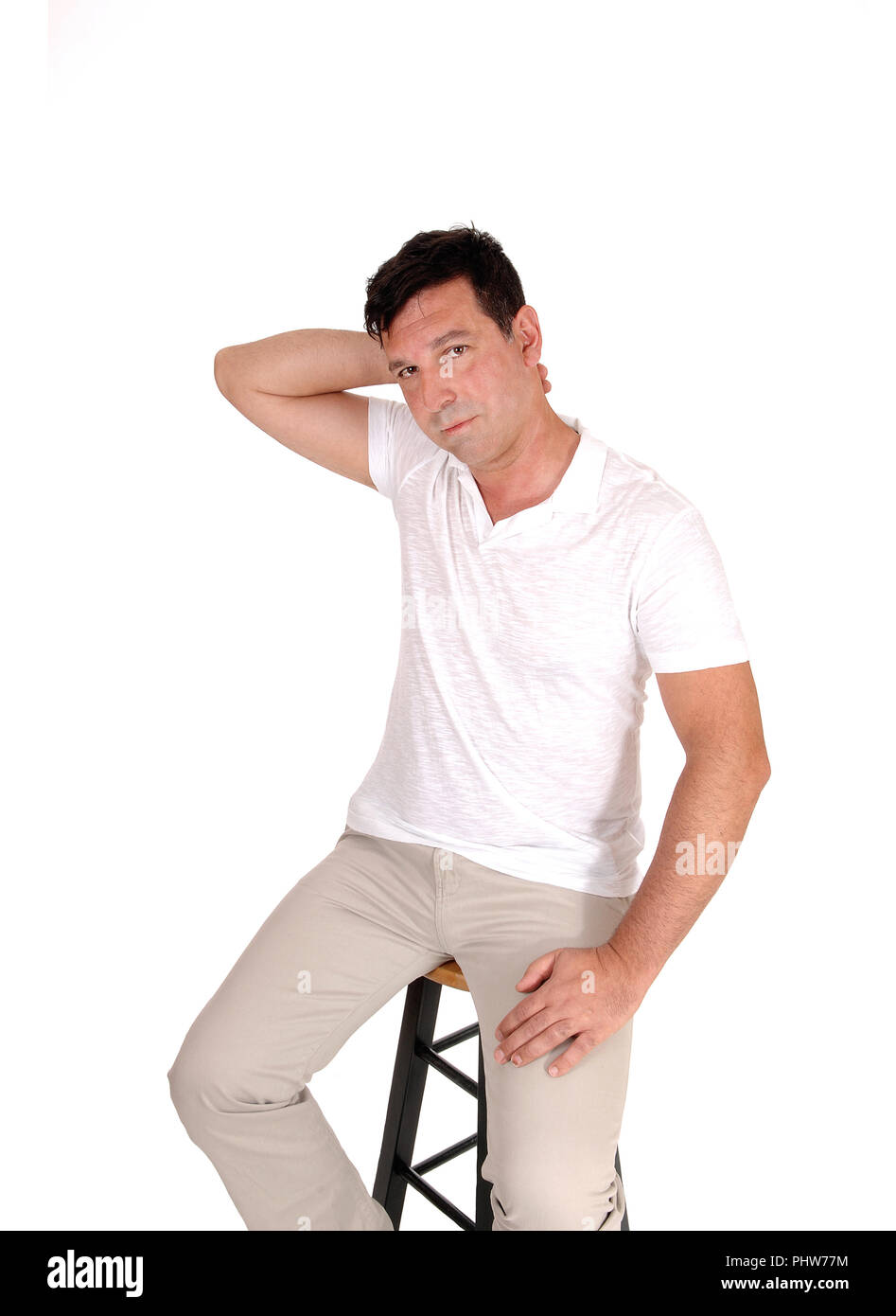 Serious looking man sitting with hand on neck Stock Photo - Alamy