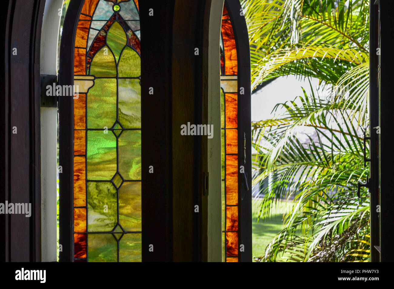 An open stained-glass window in a church, looking out on tropical ...
