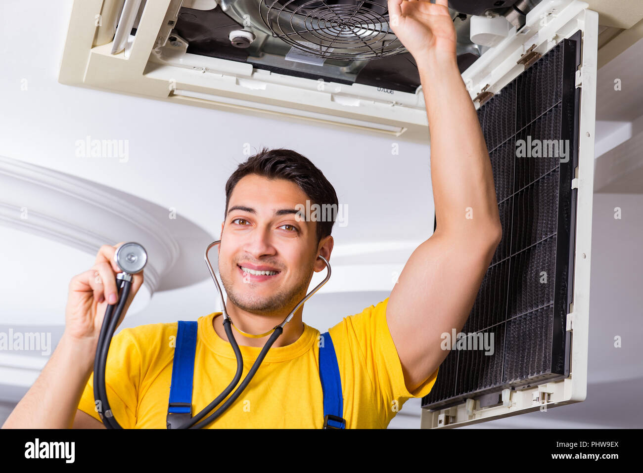 Repairman repairing ceiling air conditioning unit Stock Photo - Alamy