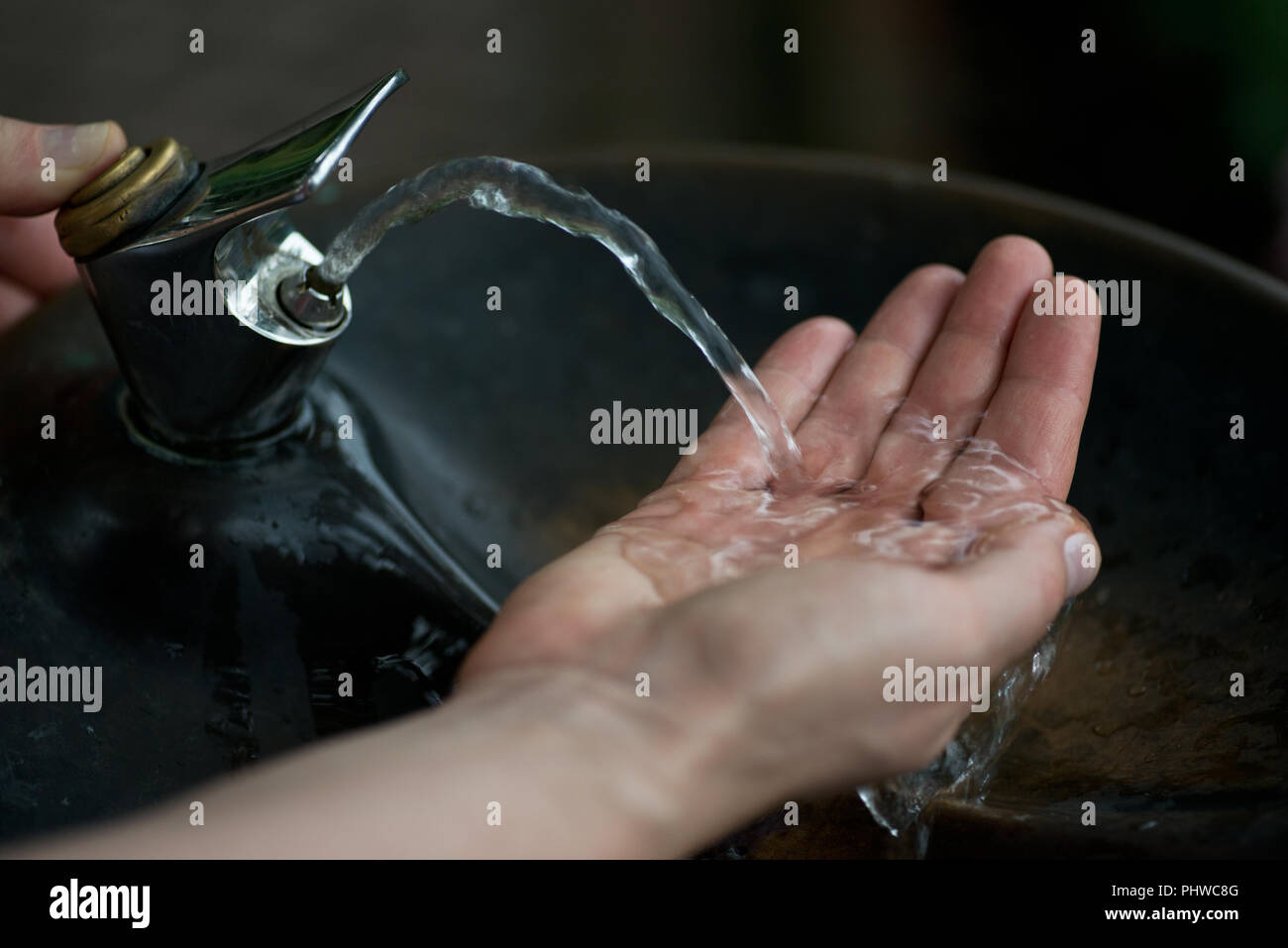 Water from drinking fountain flows into woman's hand in botanic garden ...