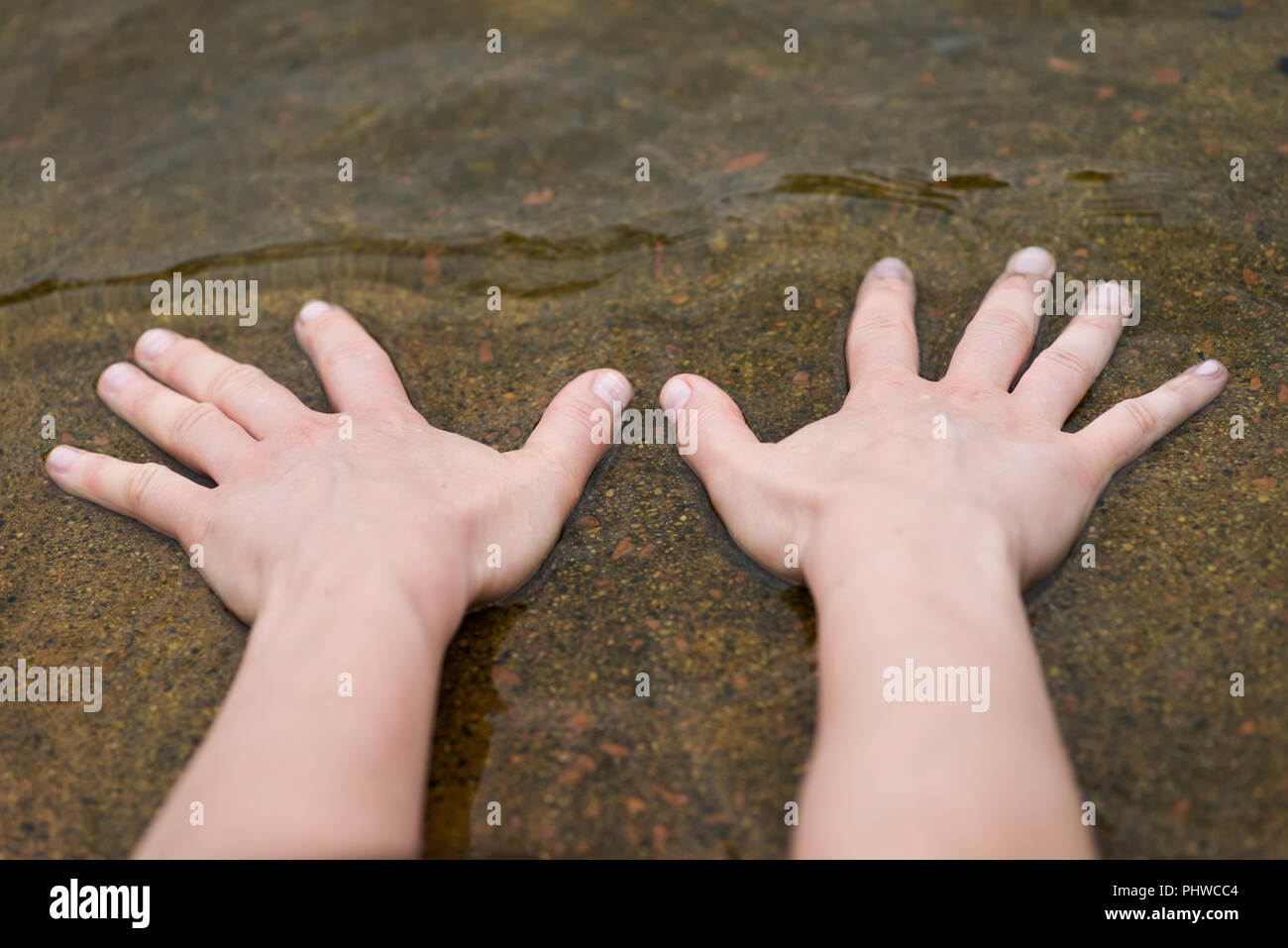 Close up of female hand touching water surface in botanic garden pond ...