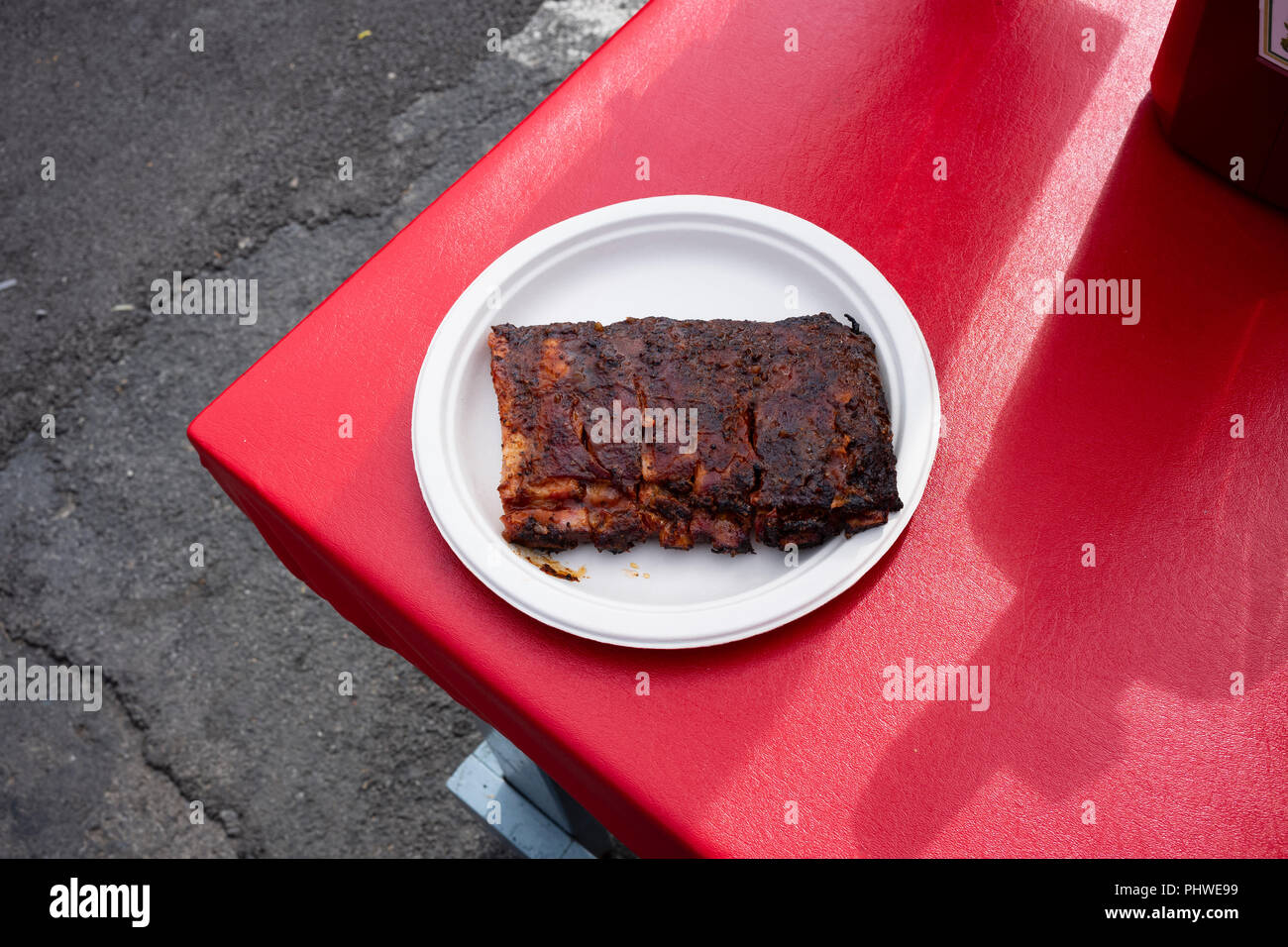 A paper plate of a half-rack barbecue ribs on a red picnic table at The ...