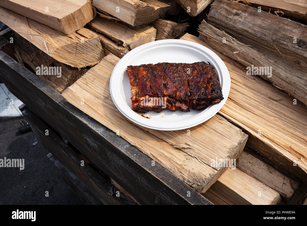 A paper plate of a half-rack barbecue ribs on a pile of firewood at The ...