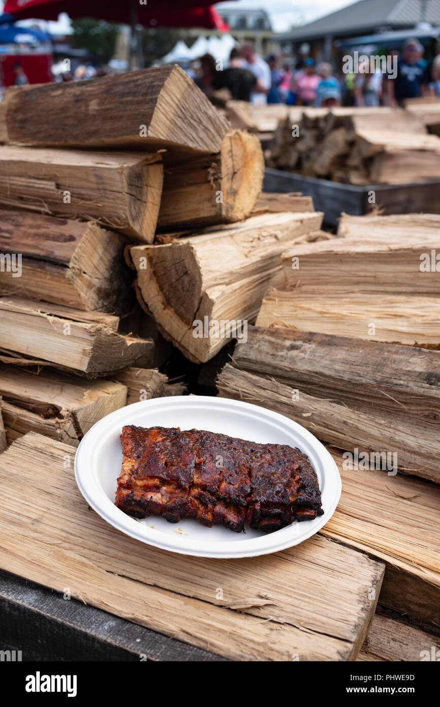 A paper plate of a half-rack barbecue ribs on a pile of firewood at The ...