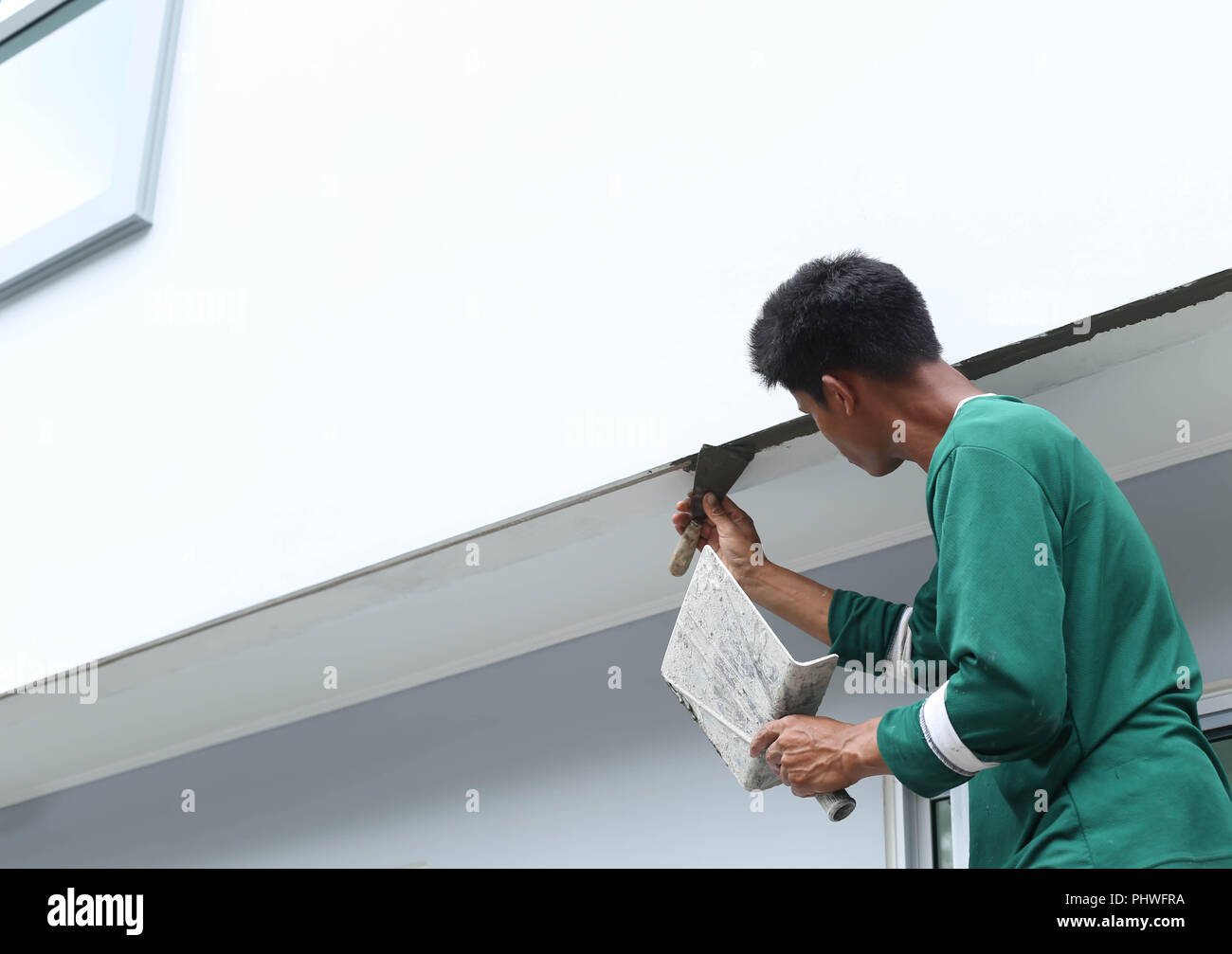 Unidentified man plastering concrete to shape the edge of the w Stock ...