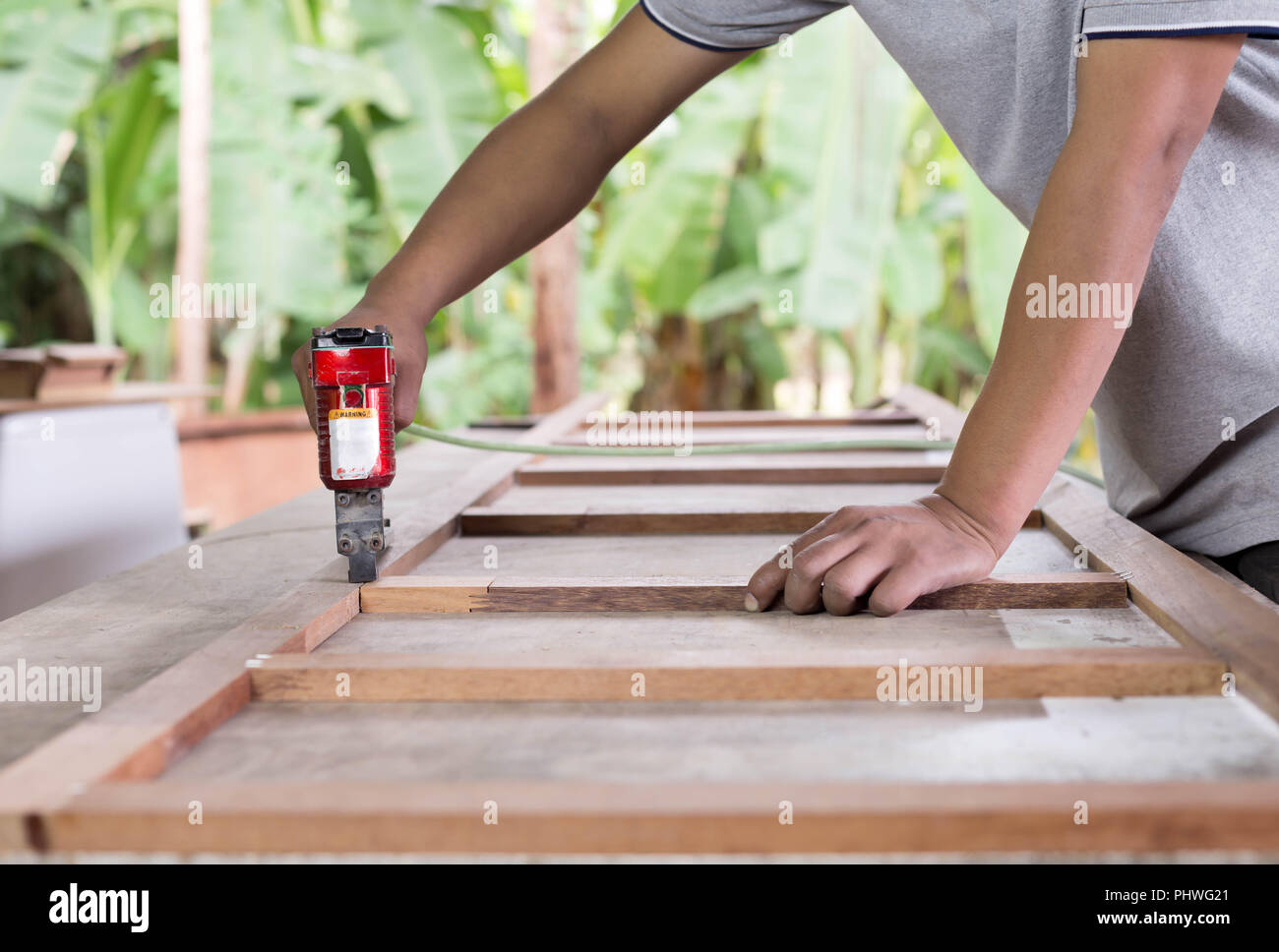 Asia carpenter use air-gun for make a furniture Stock Photo - Alamy