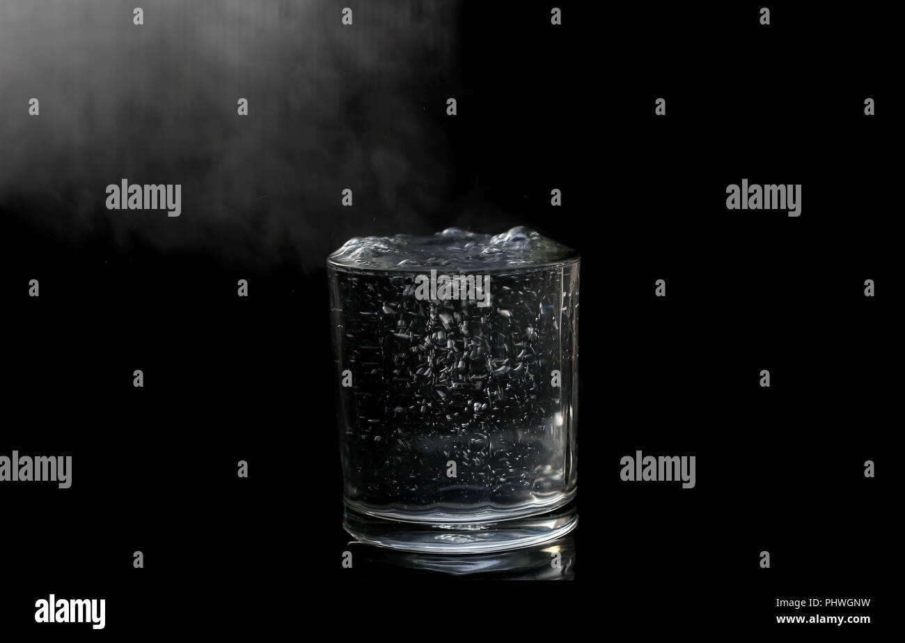 Glass with hot water on isolated in black background Stock Photo - Alamy