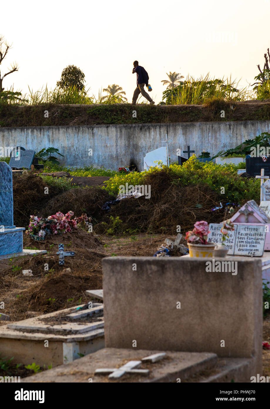 Angolan man walking o the wall of an old cemetery, Benguela Province ...