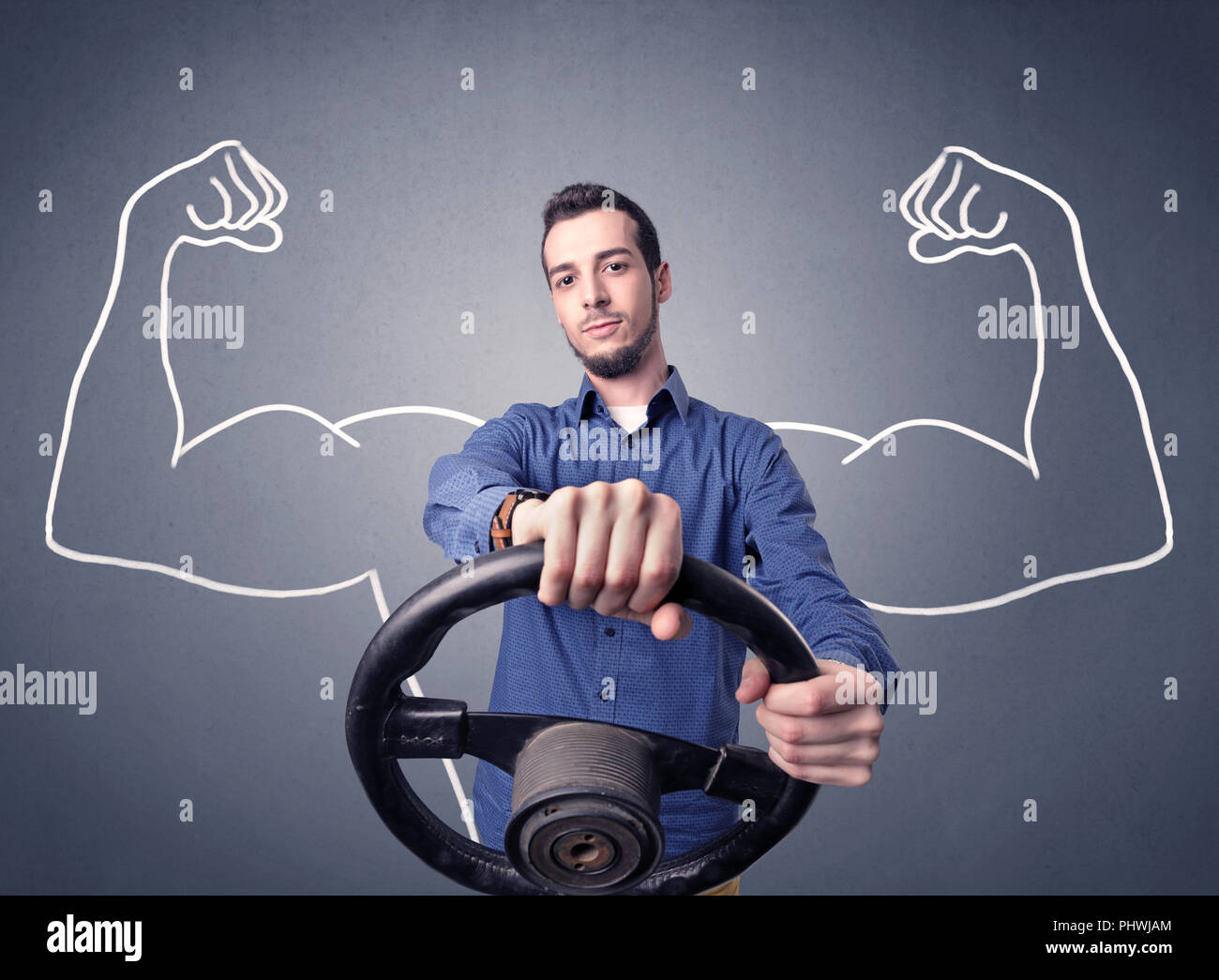 Young man holding black steering wheel with muscly arms drawn next to ...