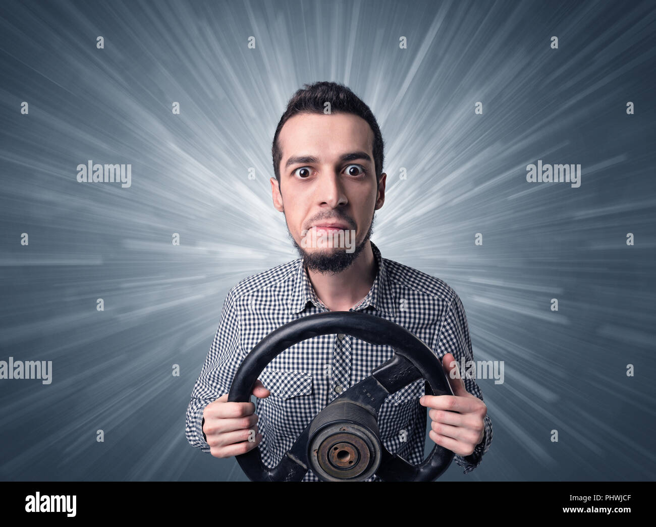 Young man holding black steering wheel with white lines behind him ...