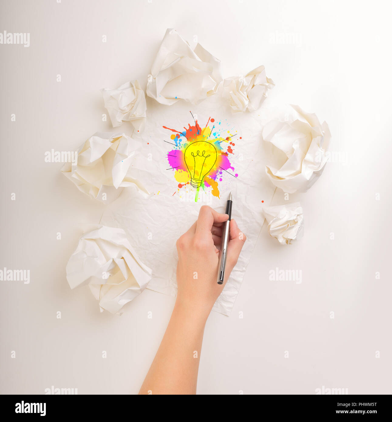 Female hand next to a few crumpled paper balls drawing a colorful ...