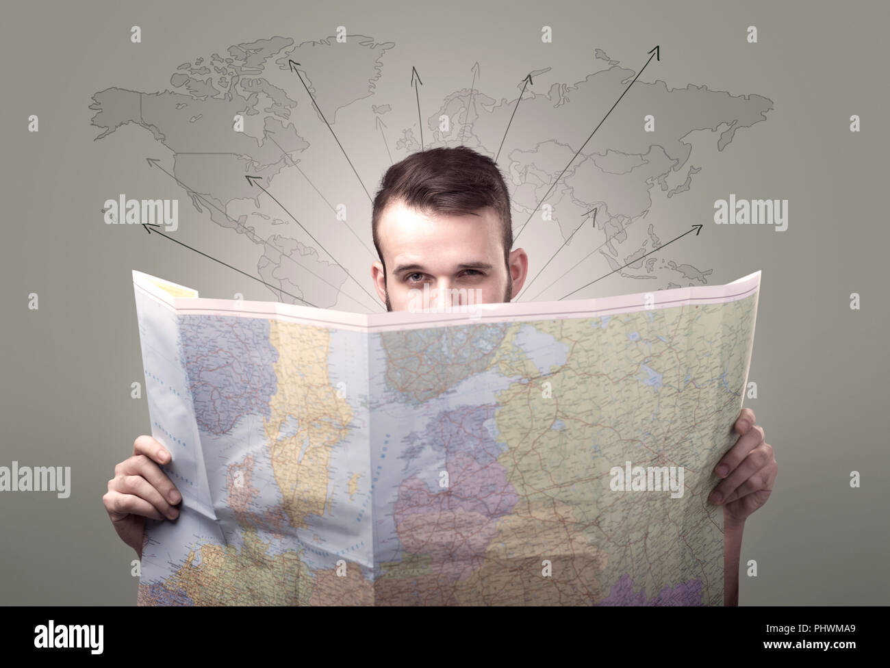 Handsome young man holding a map with world map and arrows behind him ...