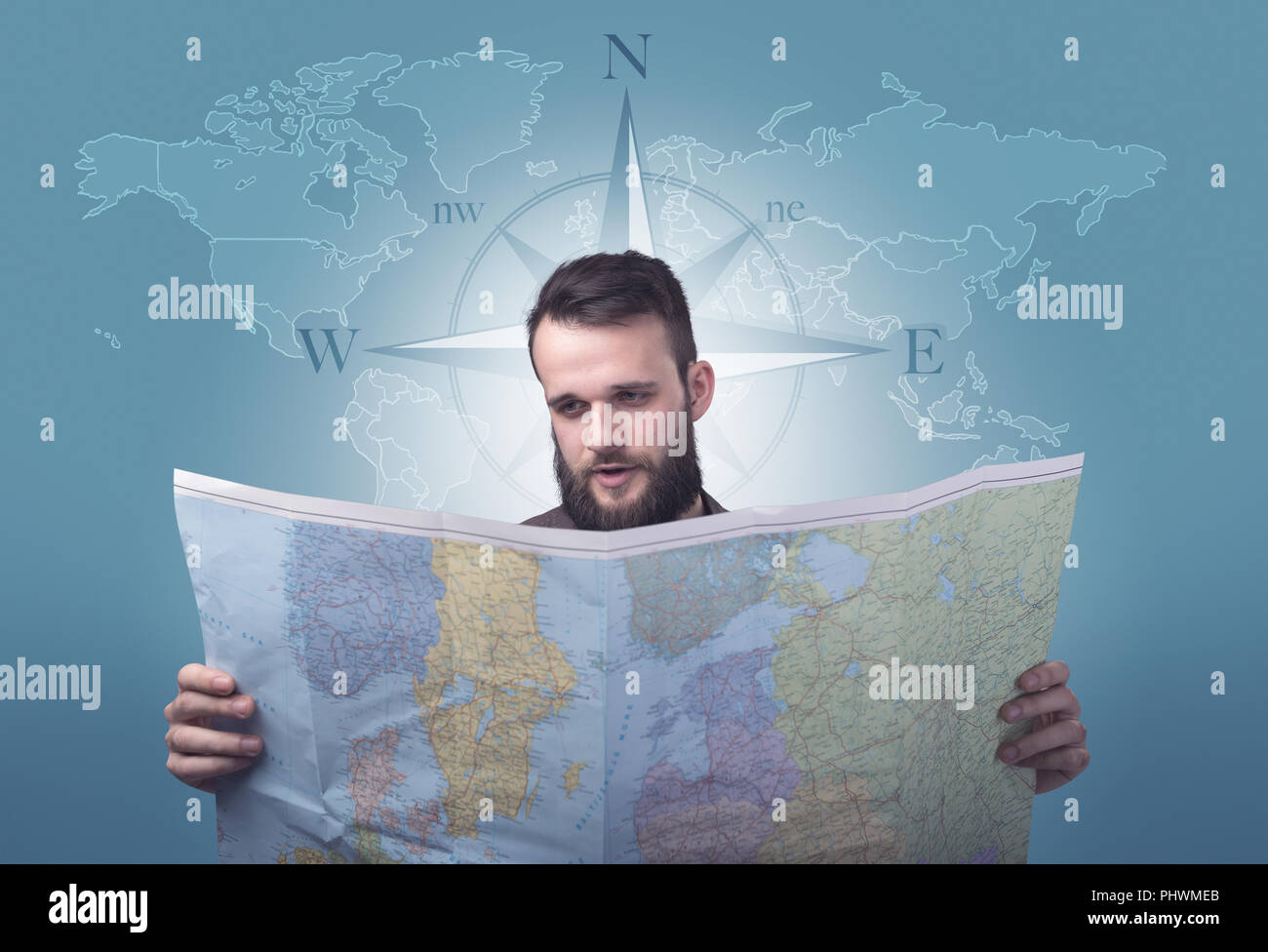 Handsome young man holding a map with a world map and a compass behind ...