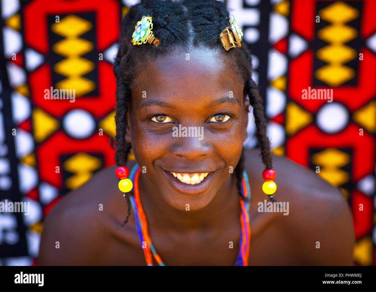 Portrait of a mudimba tribe woman in front of a colorful printed cloth ...