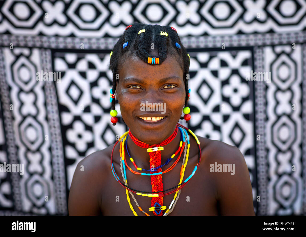 Portrait of a smiling mudimba tribe woman in front of a printed cloth ...