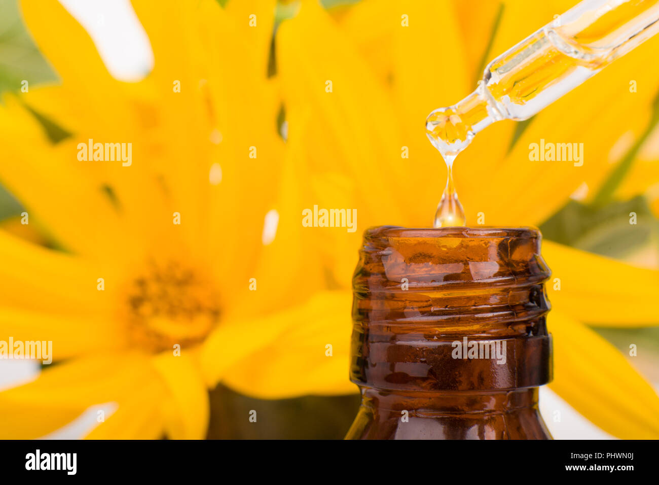 Drop falling from dropper of essential oil. Dropper over essential oil ...