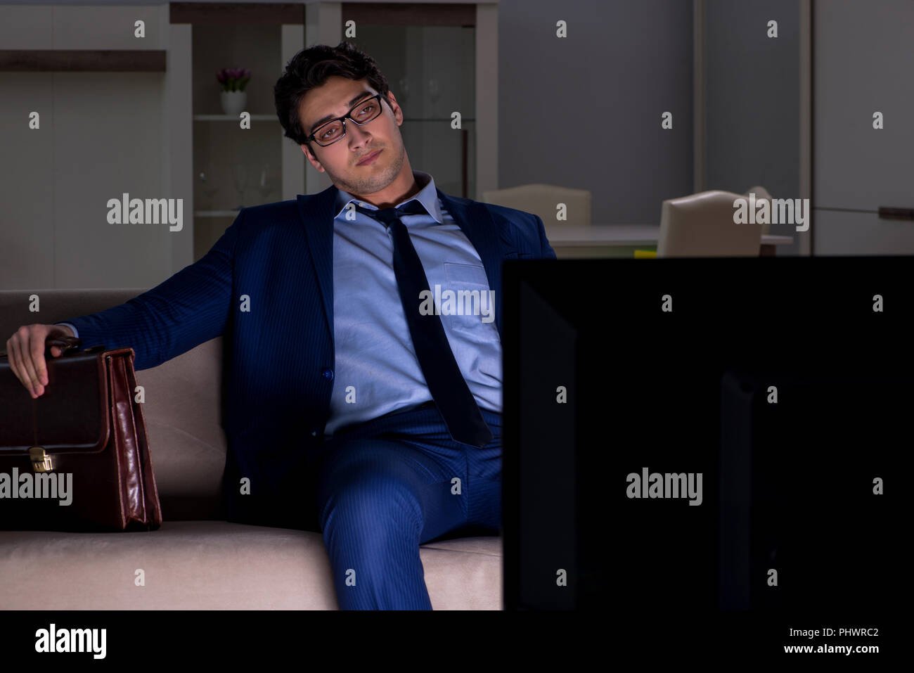Businessman watching tv at night late Stock Photo - Alamy