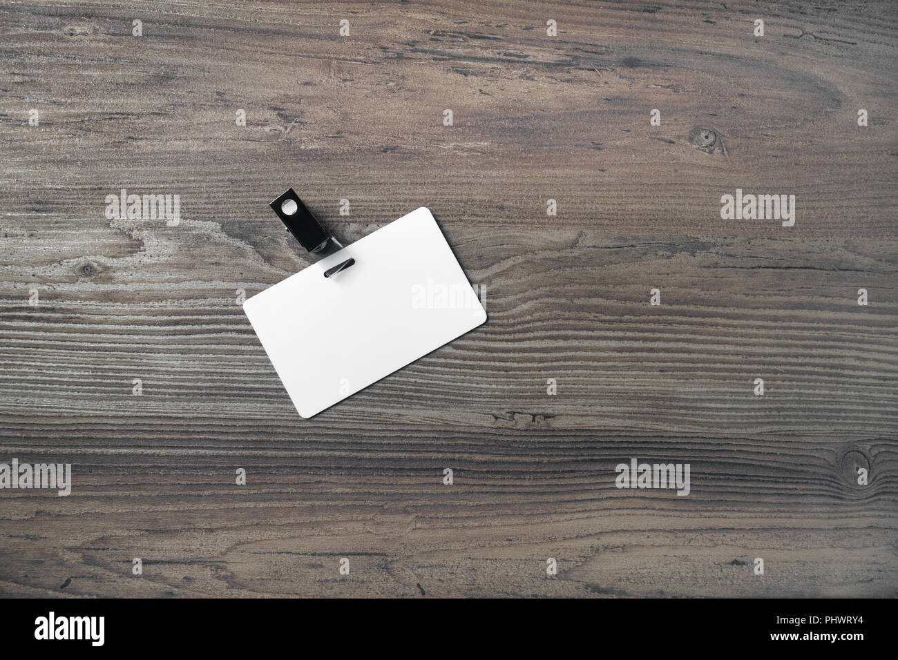 Blank badge mockup on wood table background. White plastic id card ...