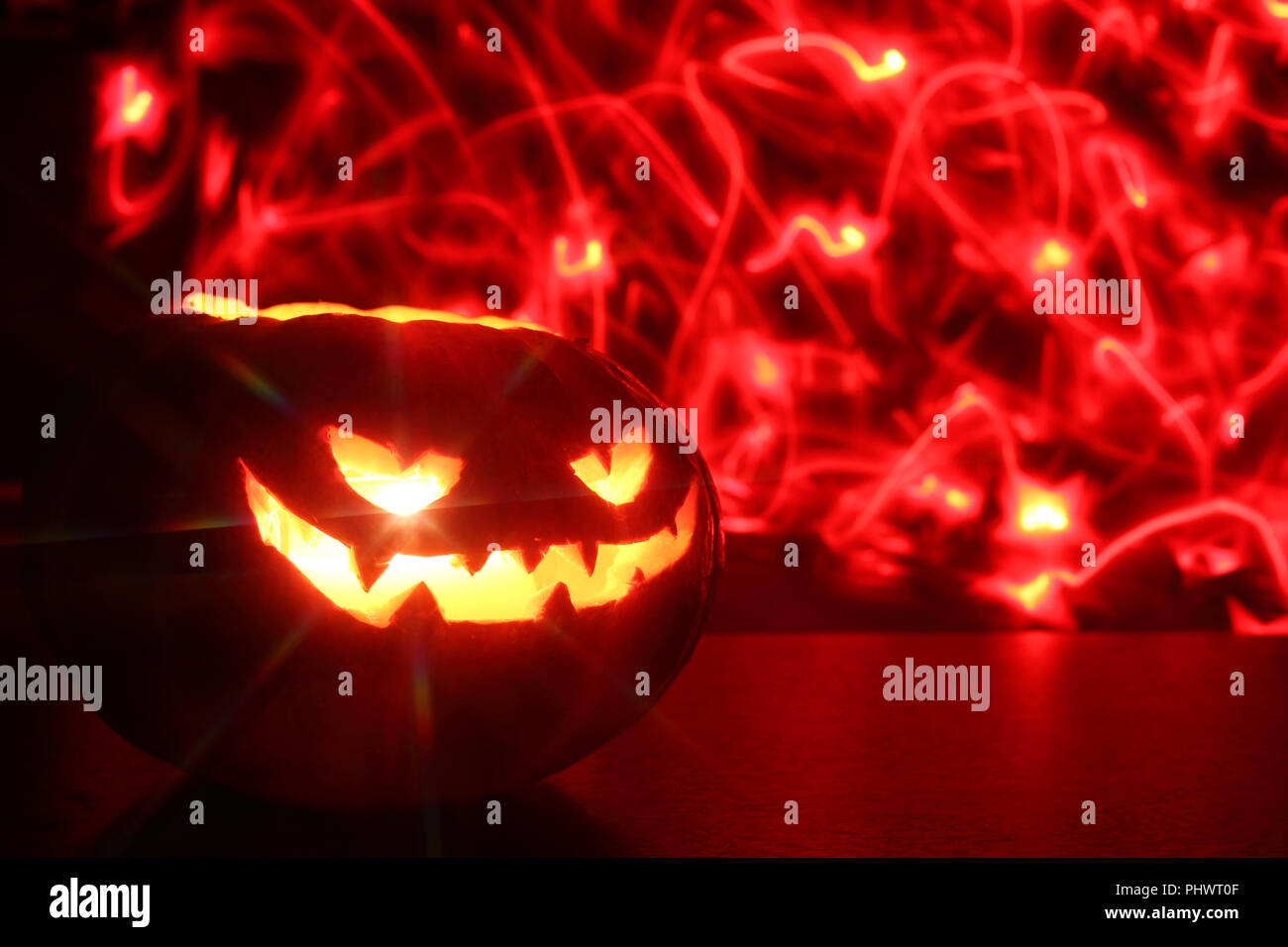 Illuminated cute halloween pumpkin and glowing lights on black ...