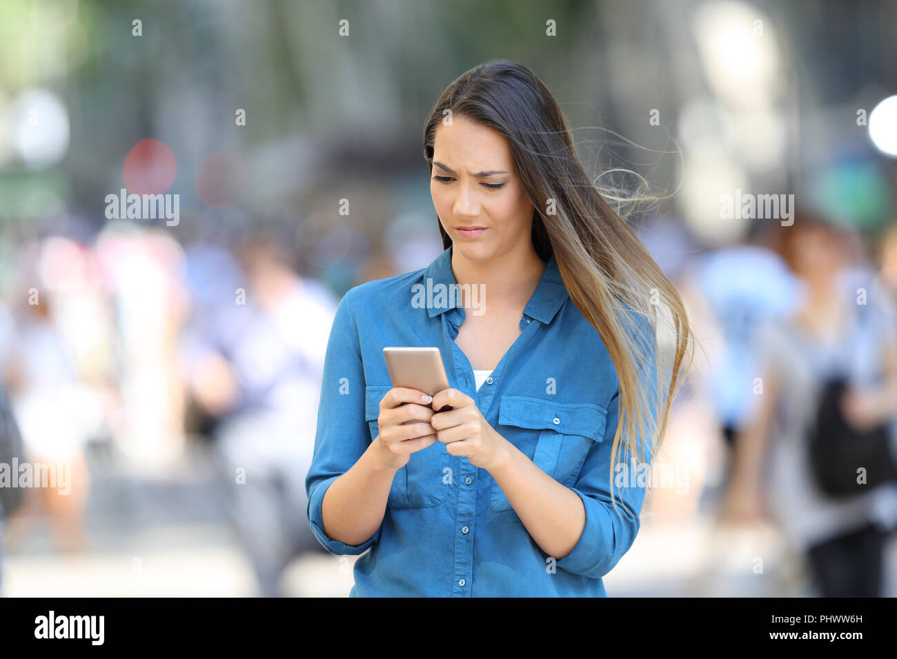 Confused woman walking and checking smart phone on the street Stock ...