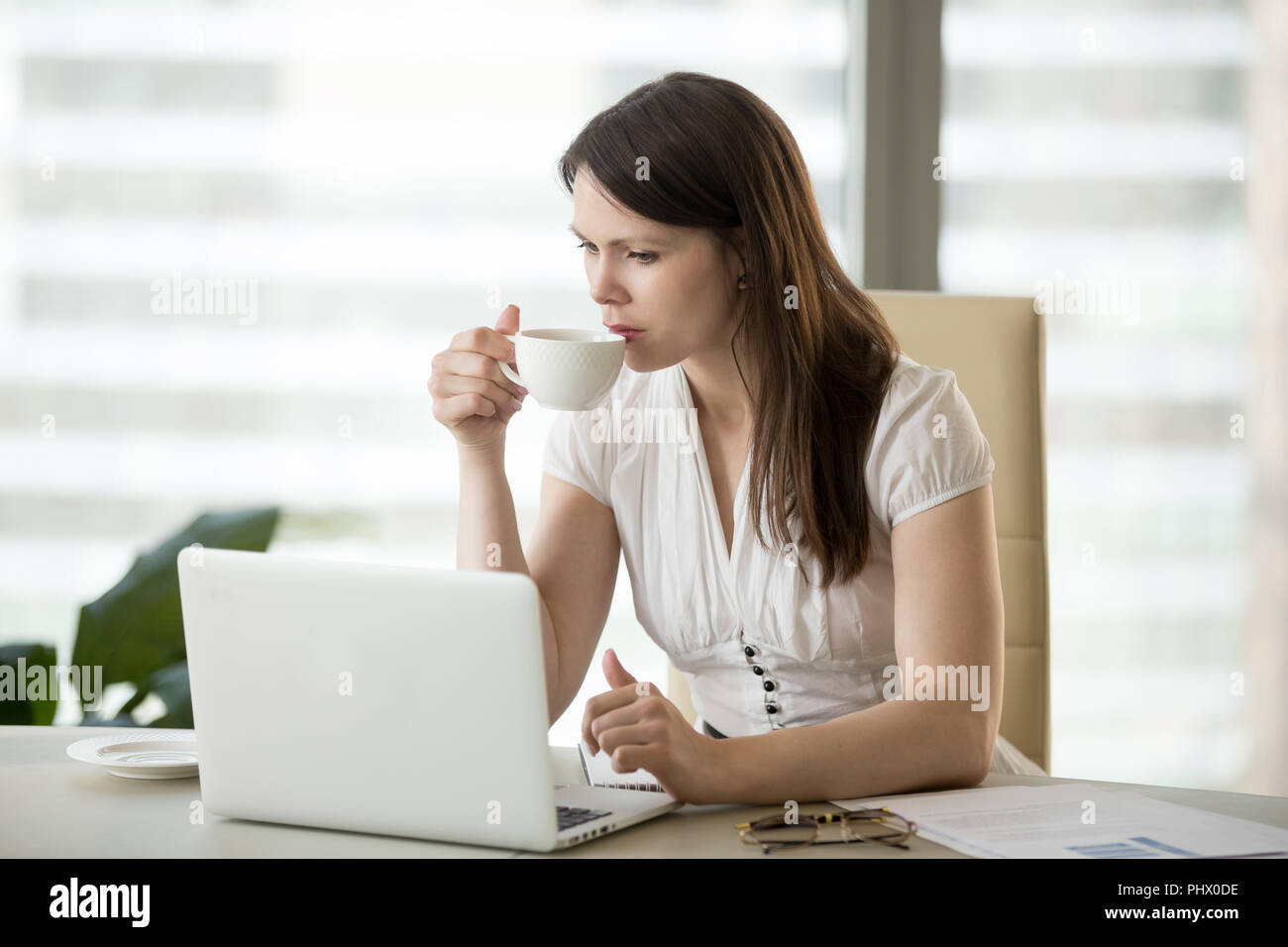 Serious Businesswoman Drinking Coffee While Working On Laptop In Stock