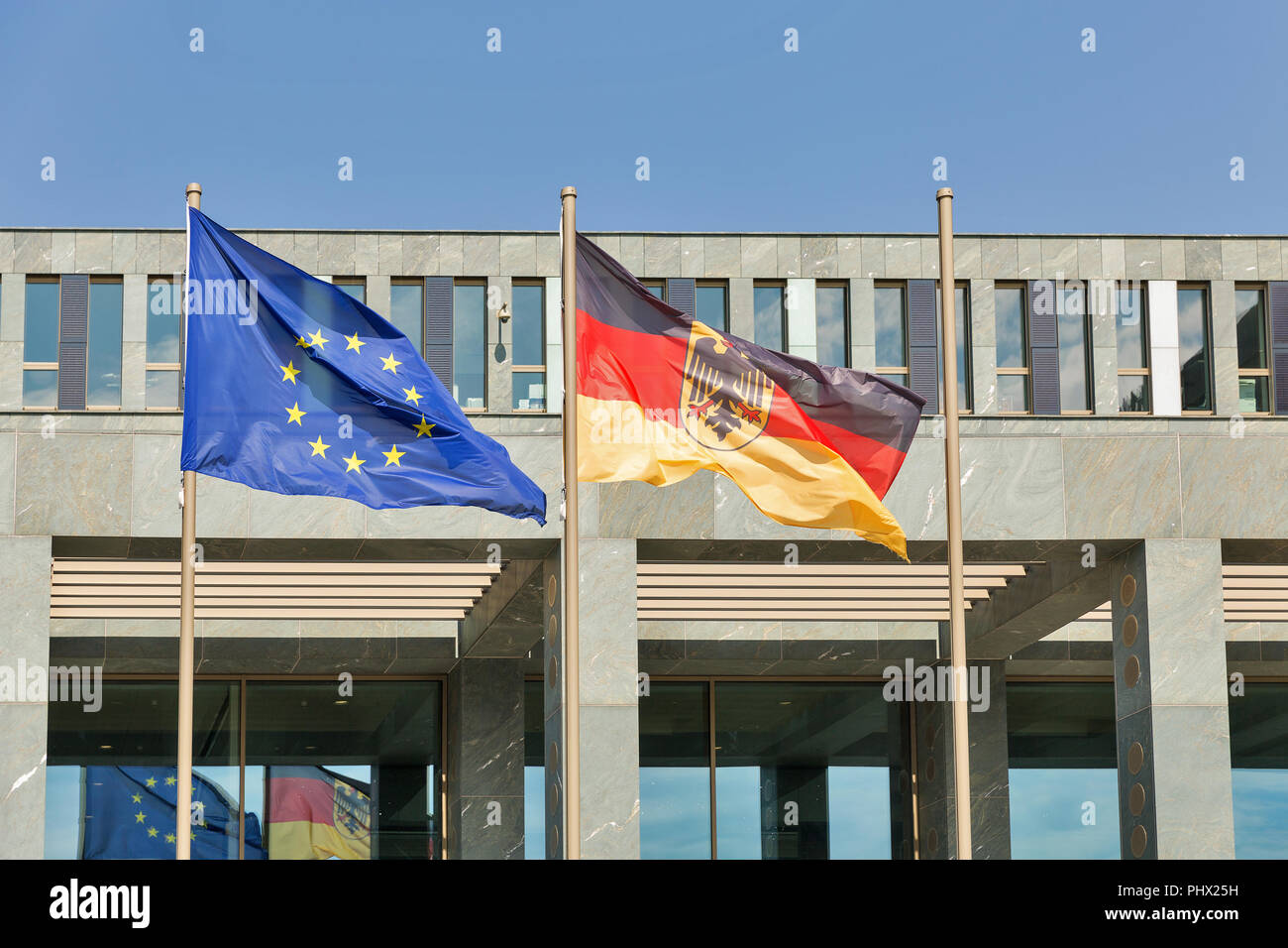 German and EU flags waving against modern office building. Berlin Mitte ...