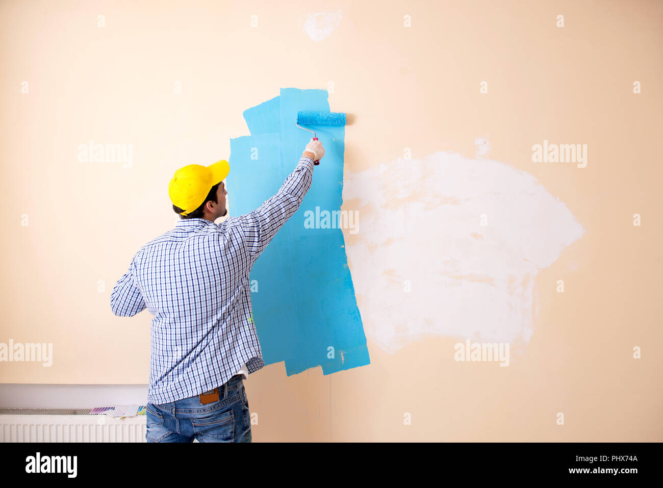Painter man painting the wall at home Stock Photo - Alamy