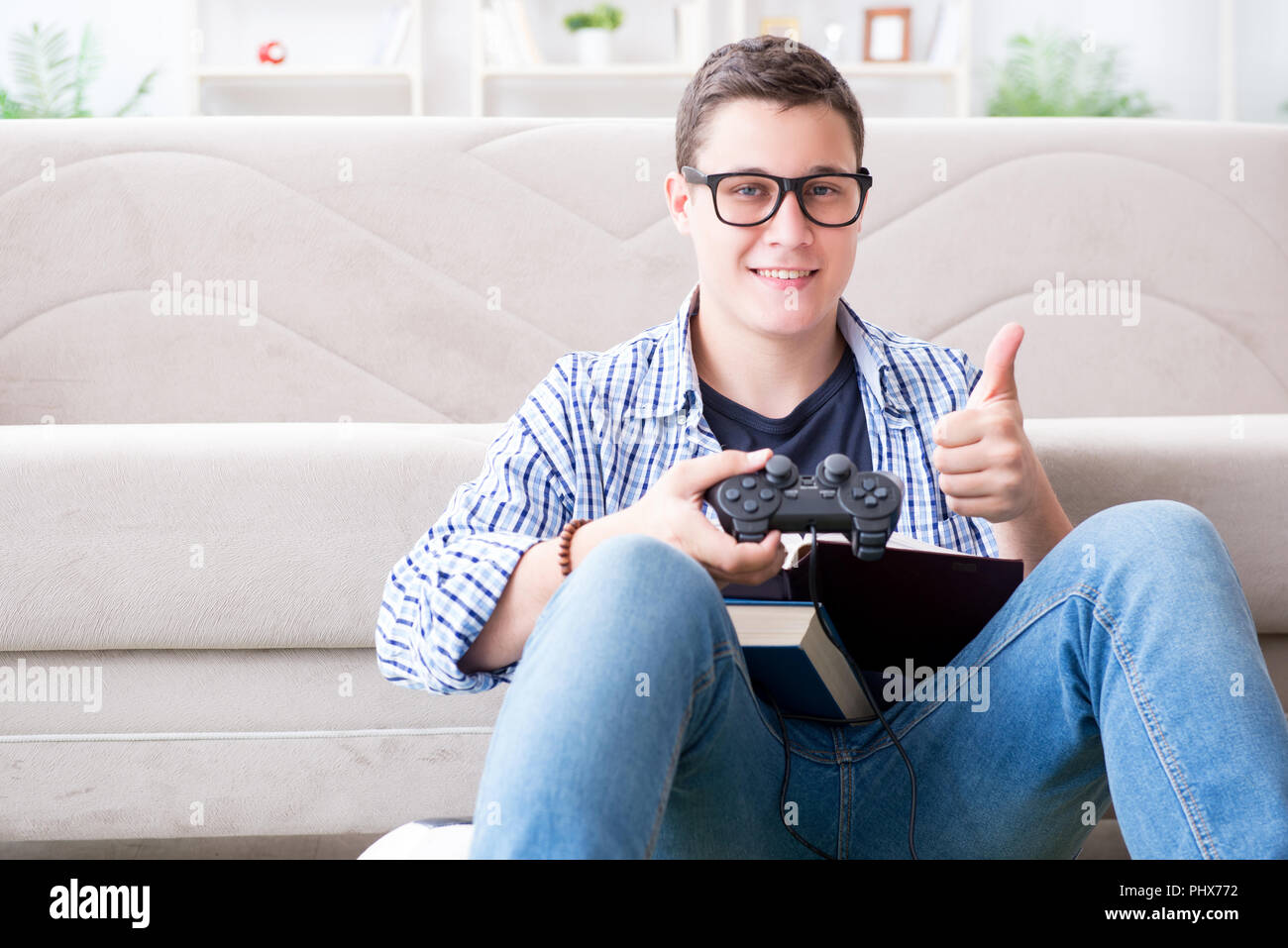 Young student trying to balance studying and playing games Stock Photo ...