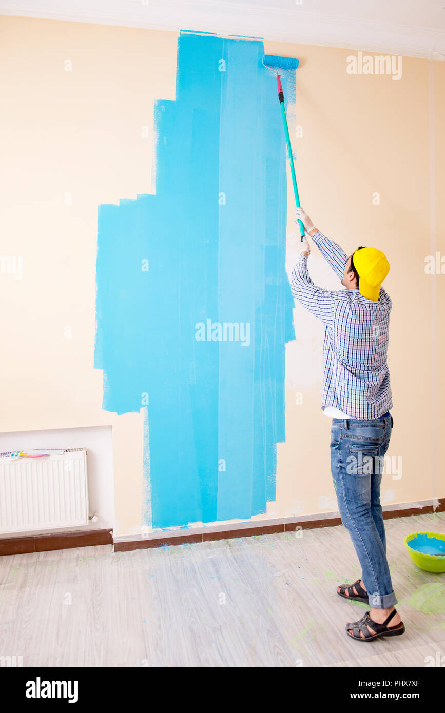 Painter man painting the wall at home Stock Photo - Alamy