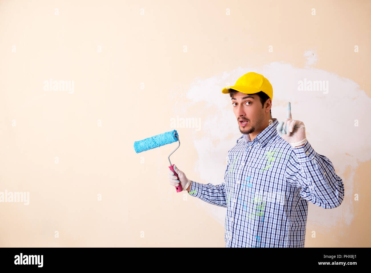 Painter man painting the wall at home Stock Photo - Alamy