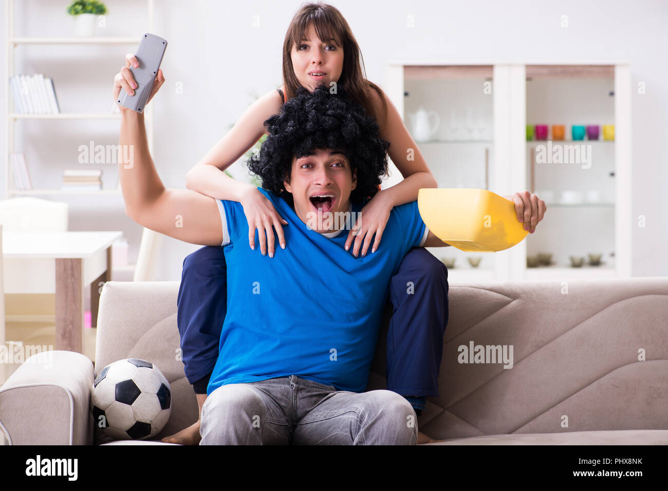 Young man watching football with his wife at home Stock Photo - Alamy