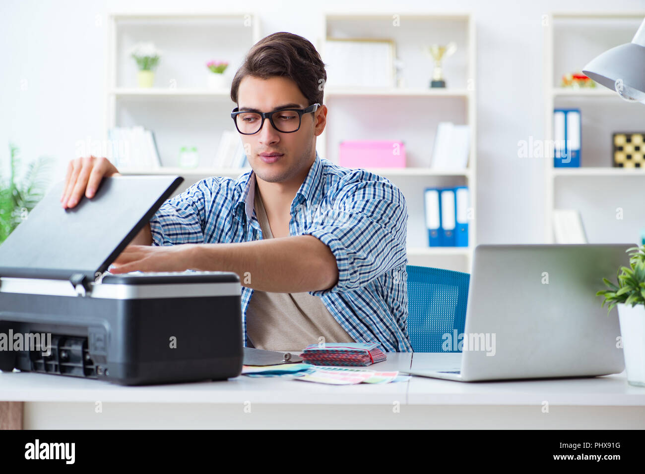 Young man employee working at copying machine in the office Stock Photo ...