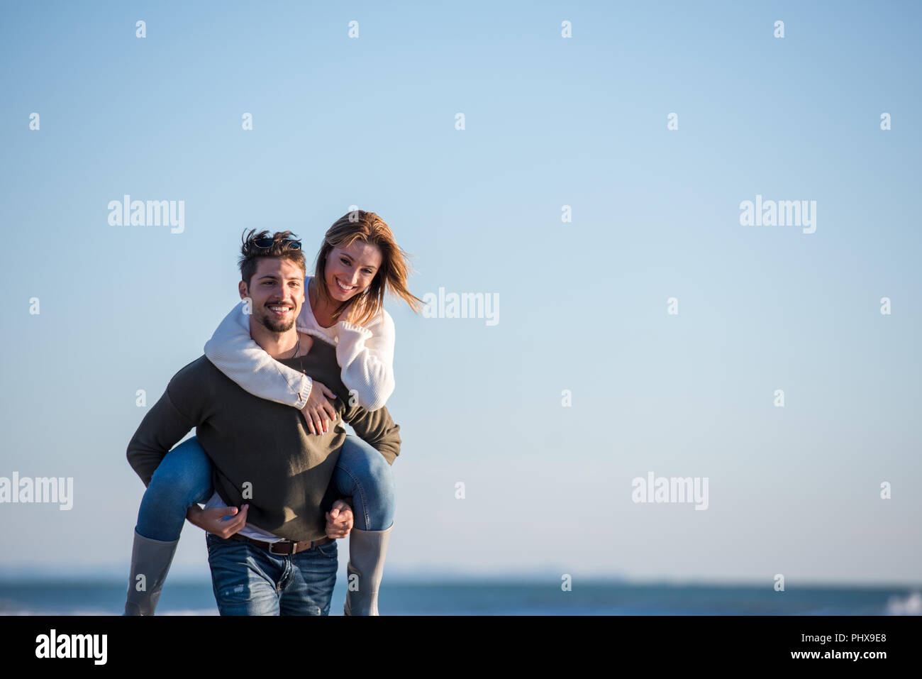 Men Giving Piggy Back Rides to his girlfriend At Sunset By The Sea ...