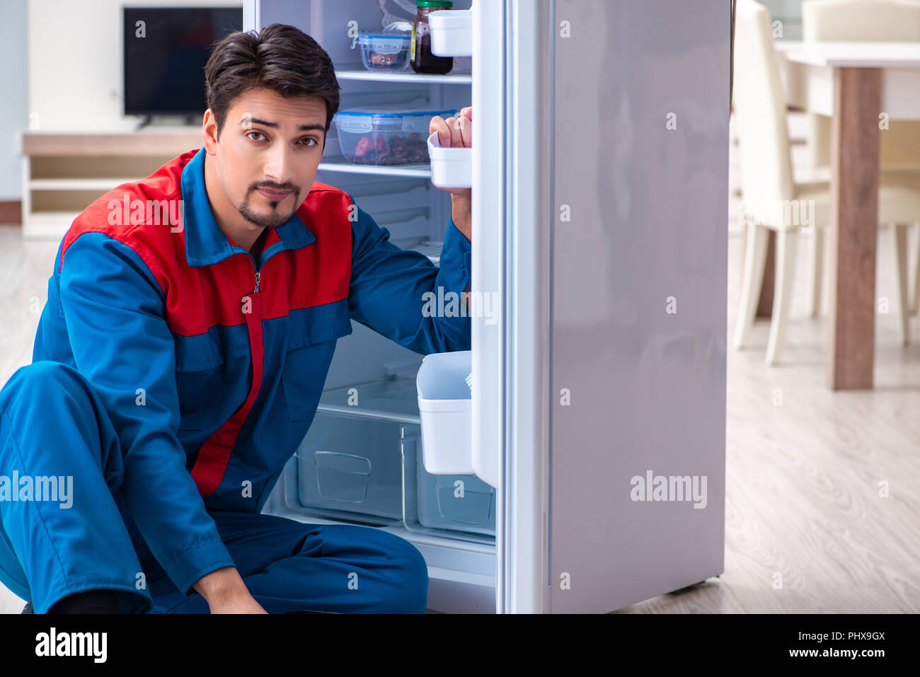 Professional contractor repairing broken fridge Stock Photo - Alamy