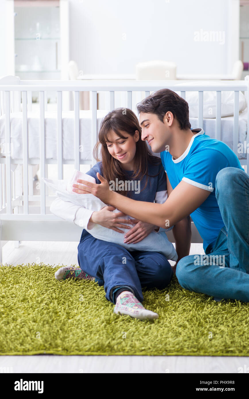 Young parents with their newborn baby sitting on the carpet Stock Photo ...