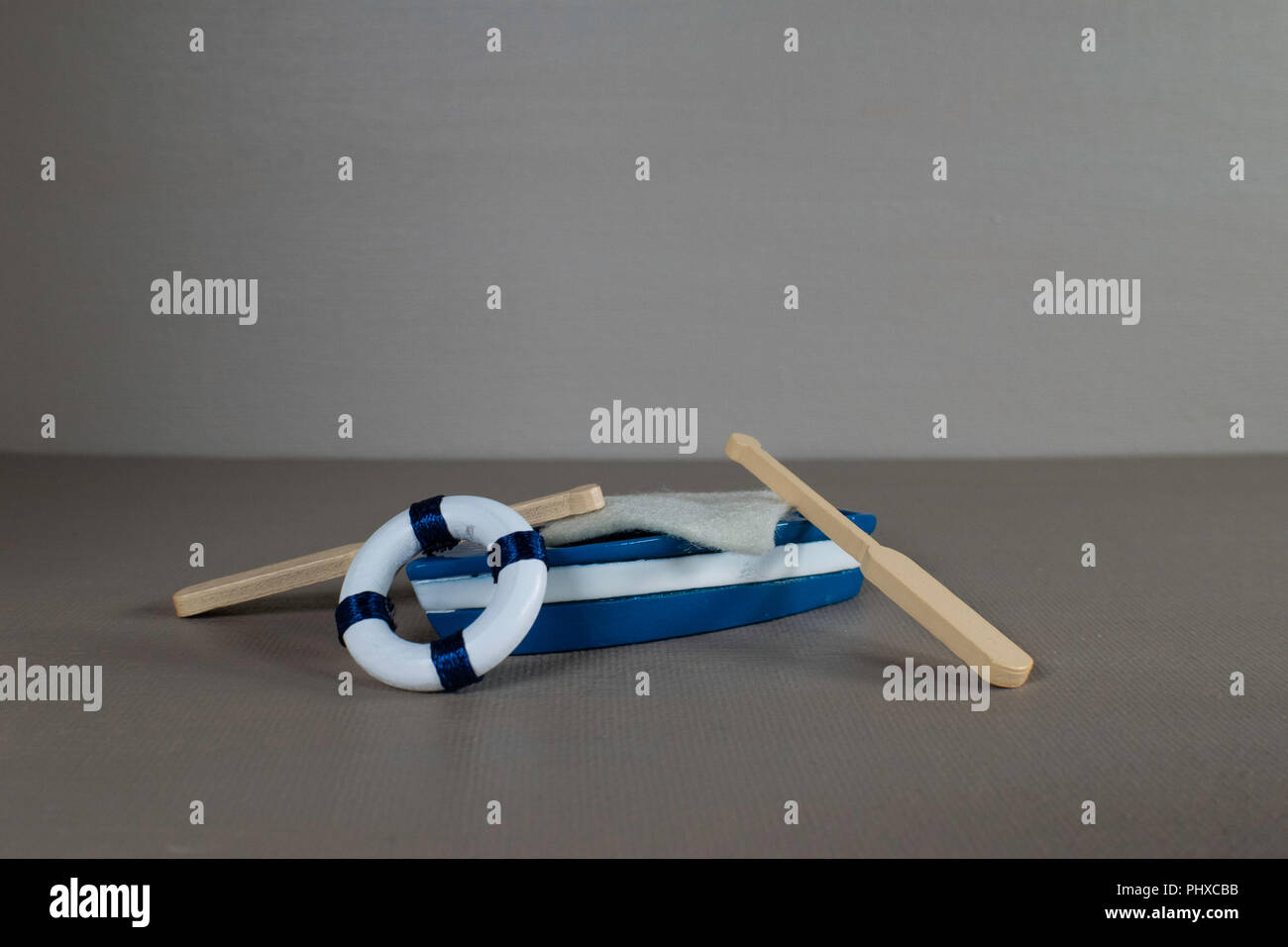 Small blue toy boat with oars and buoy with a brown background Stock ...