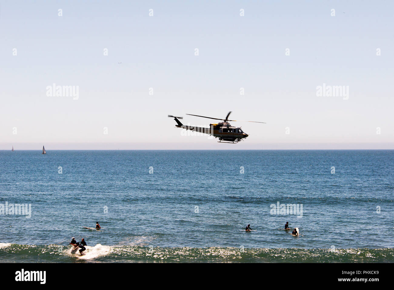 A view of a flying fire helicopter over the Malibu beach and surfers in ...