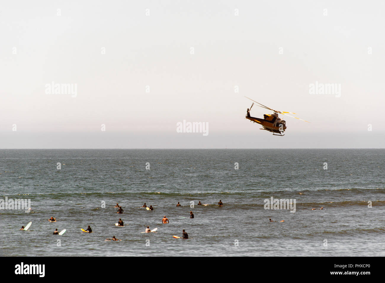 A view of a flying fire helicopter over the Malibu beach and surfers in ...