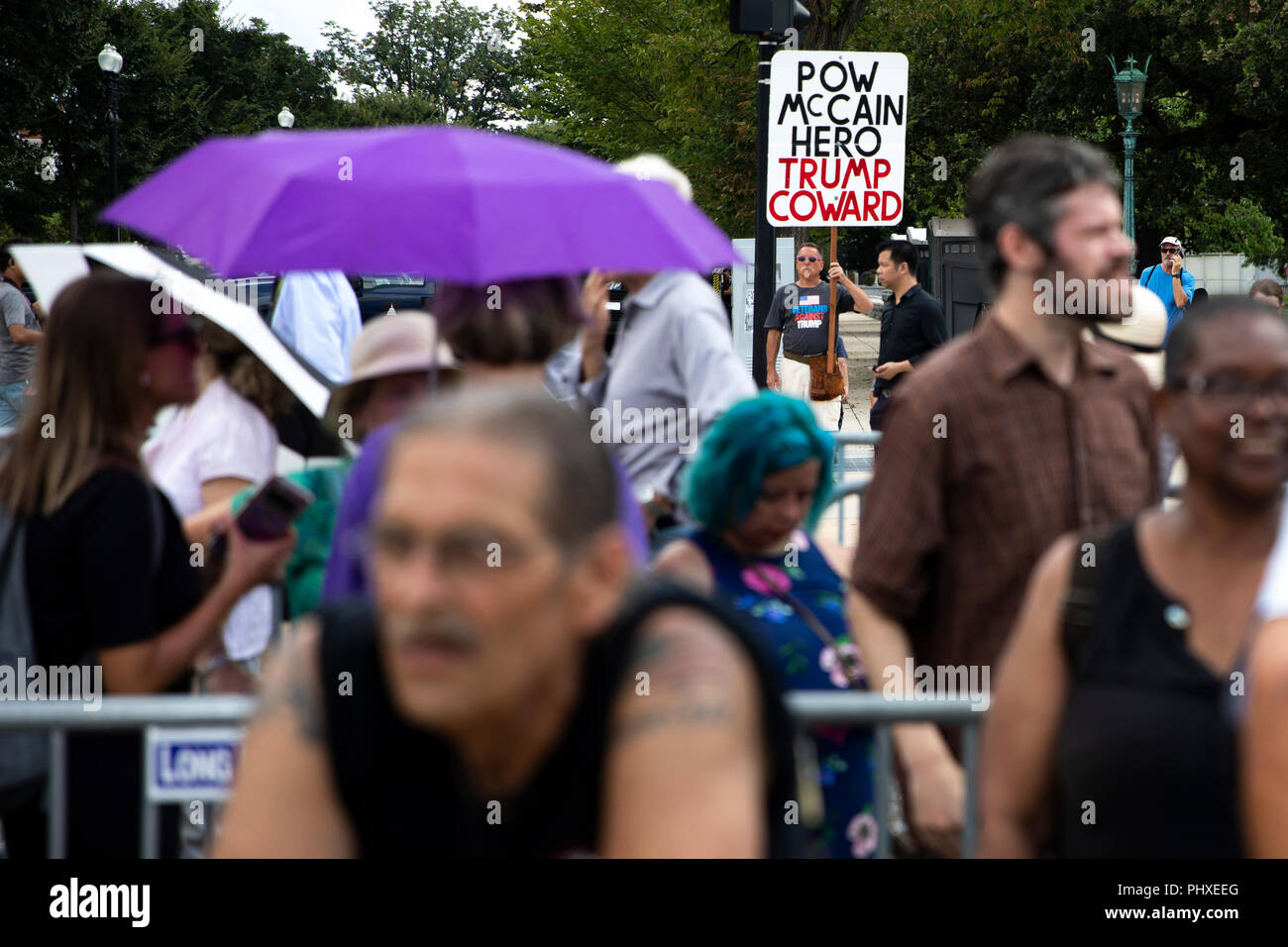 A demonstrators holds a protest sign as mourners line up outside the ...