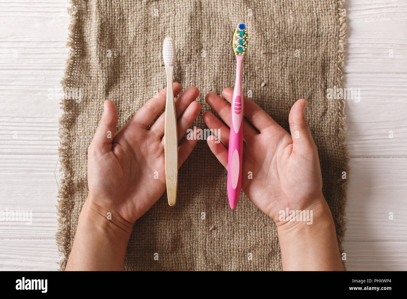 hand holding eco natural bamboo toothbrush and in other hand plastic ...
