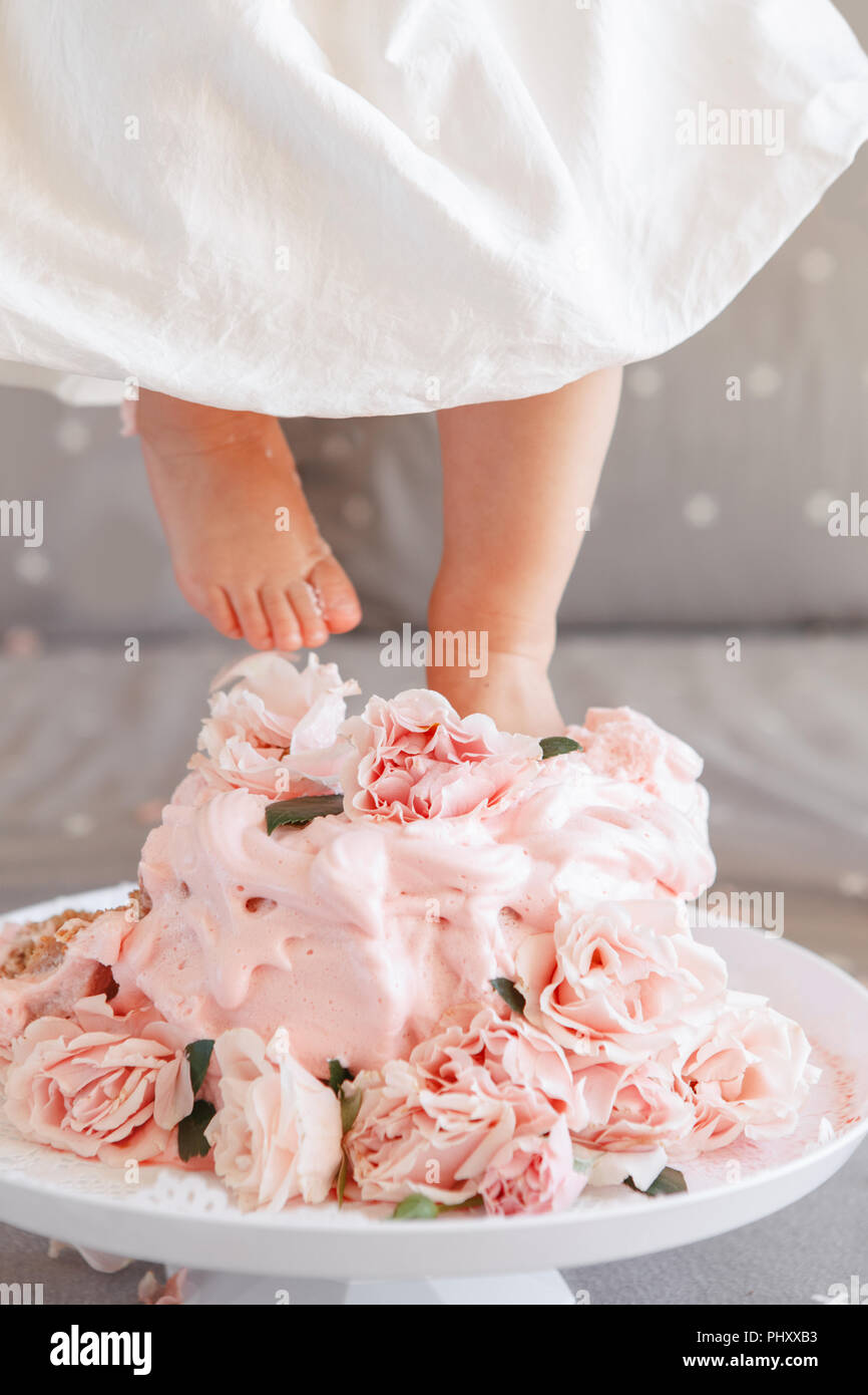 Closeup shot image of baby girl legs feet stepping in cake during her ...