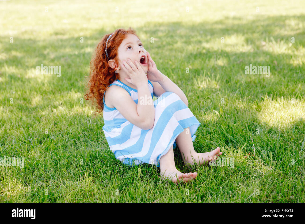 Portrait of cute adorable surprised little red-haired Caucasian girl ...